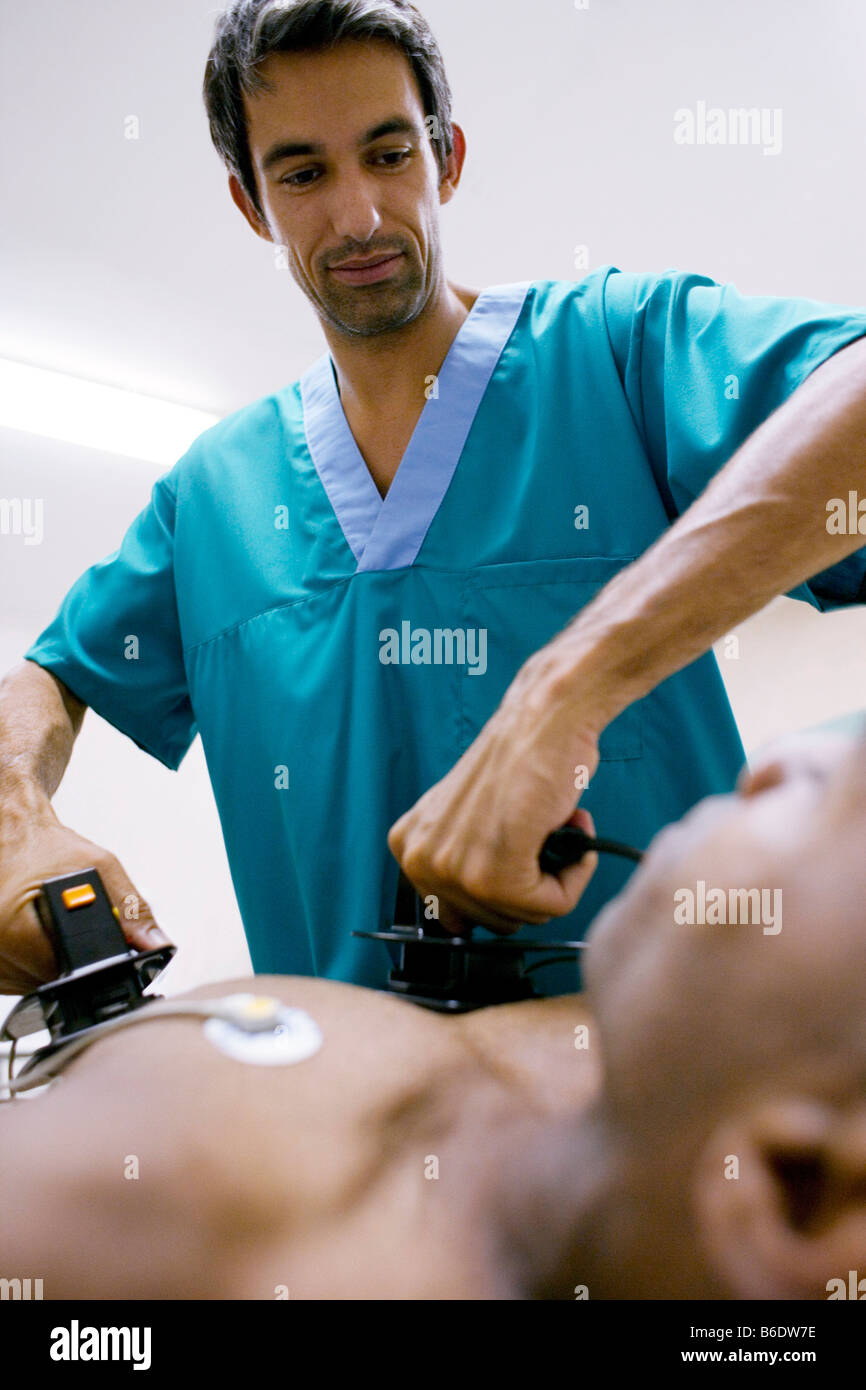Emergency defibrillation. Man recieving emergency defibrillation from a ...
