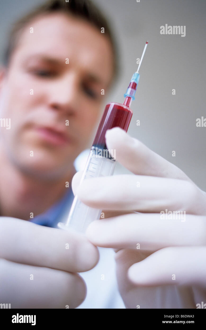 Blood sample. Doctor holding a syringe full of blood Stock Photo - Alamy