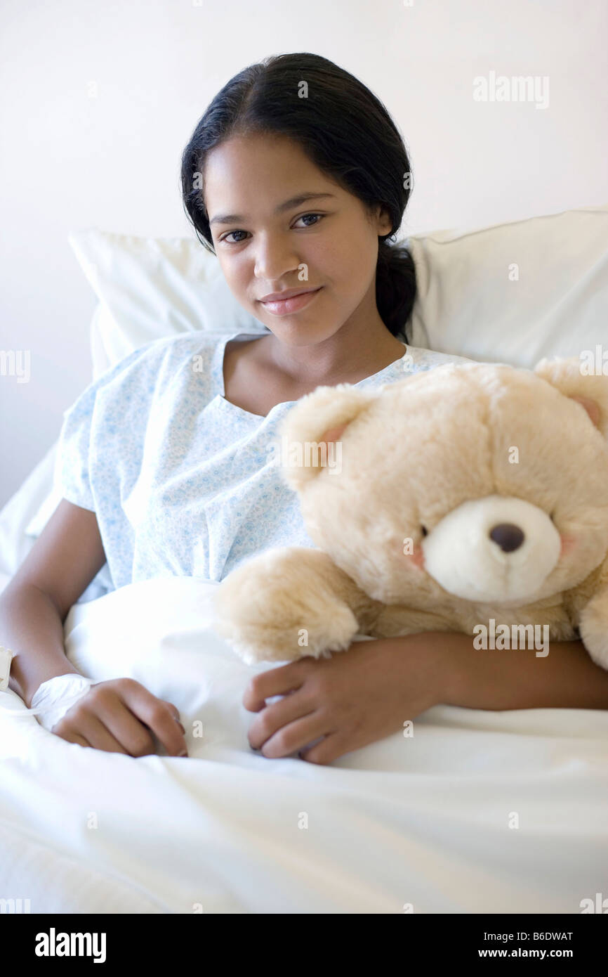 Teenage hospital patient. Teenagegirl cuddling a teddy bear in a ...