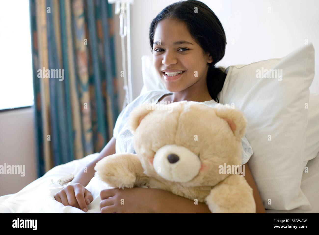 Teenage hospital patient. Teenagegirl cuddling a teddy bear in a ...