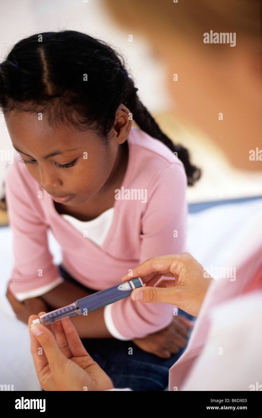 Insulin syringe. Diabetic 9-year- old girl listening to her doctor ...