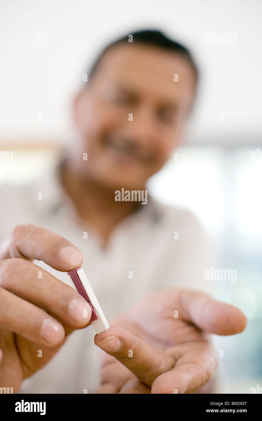 Blood glucose test. Man using a pen-like lancing device to prick his ...
