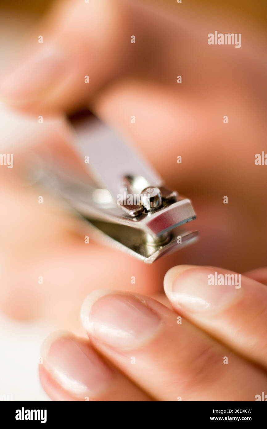 Cutting nails. Woman cutting her finger nails using a nail clipper ...
