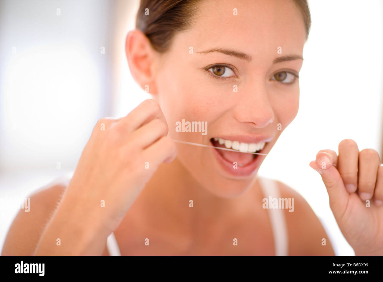 Woman flossing her teeth. This cleaning technique removes food ...