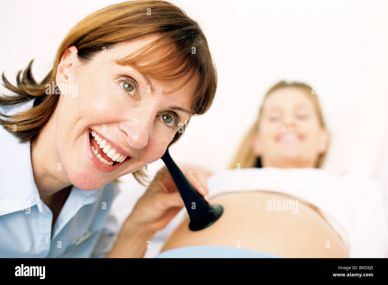 Obstetric examination. Midwife using a pinard pressed to a pregnant ...