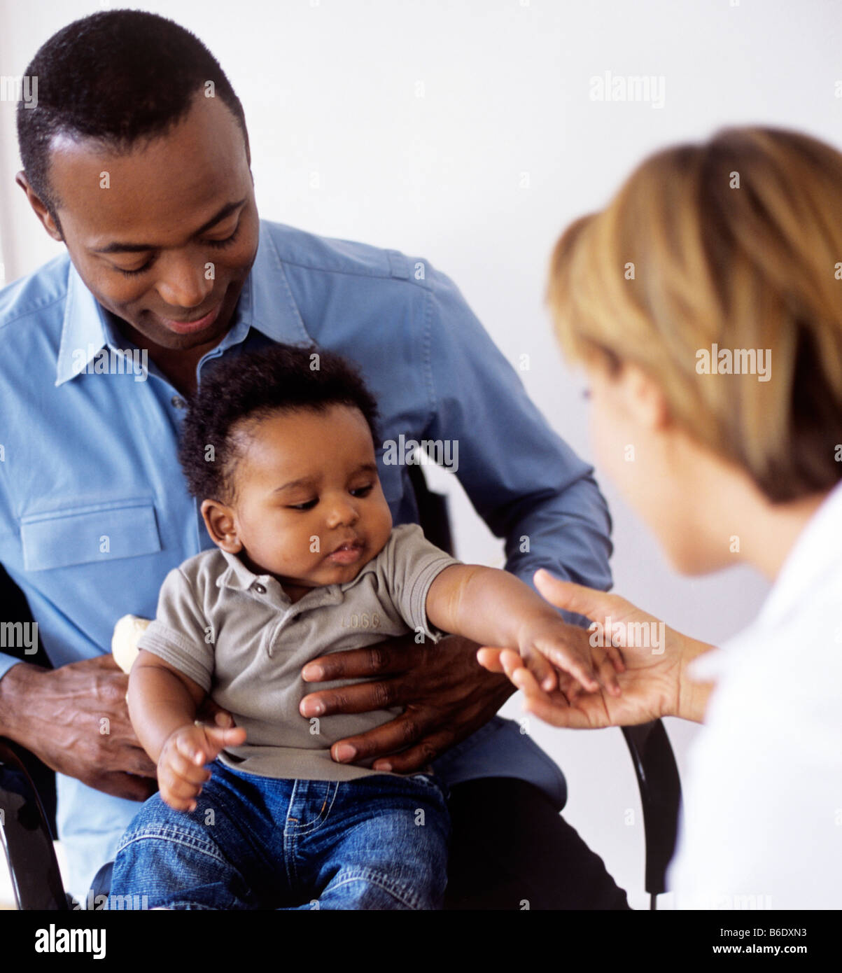 Paediatric examination. Doctor examining a 5-month-old boy sitting in ...
