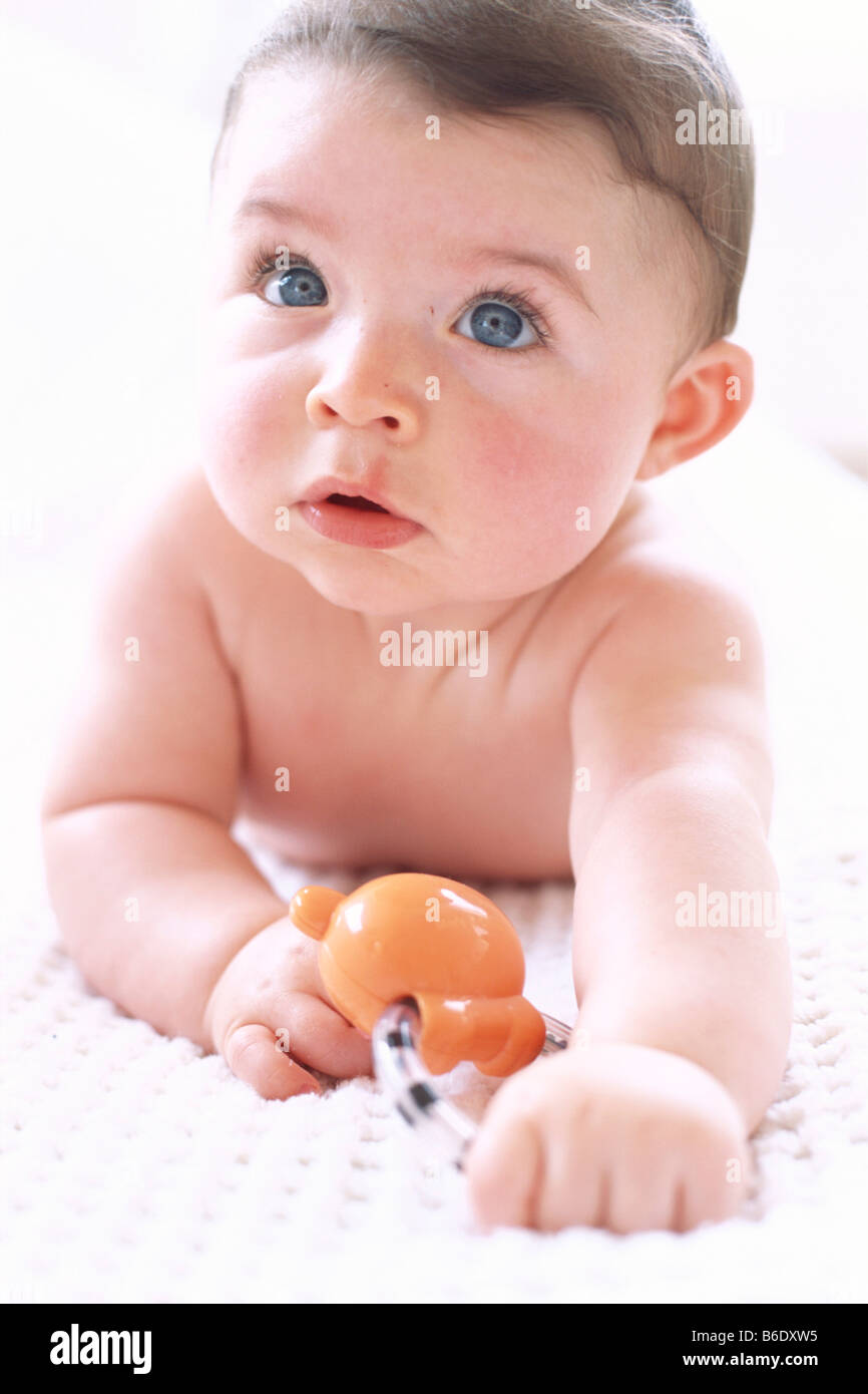 Baby boy. Distracted 6-month-old baby boy holding a toy Stock Photo - Alamy