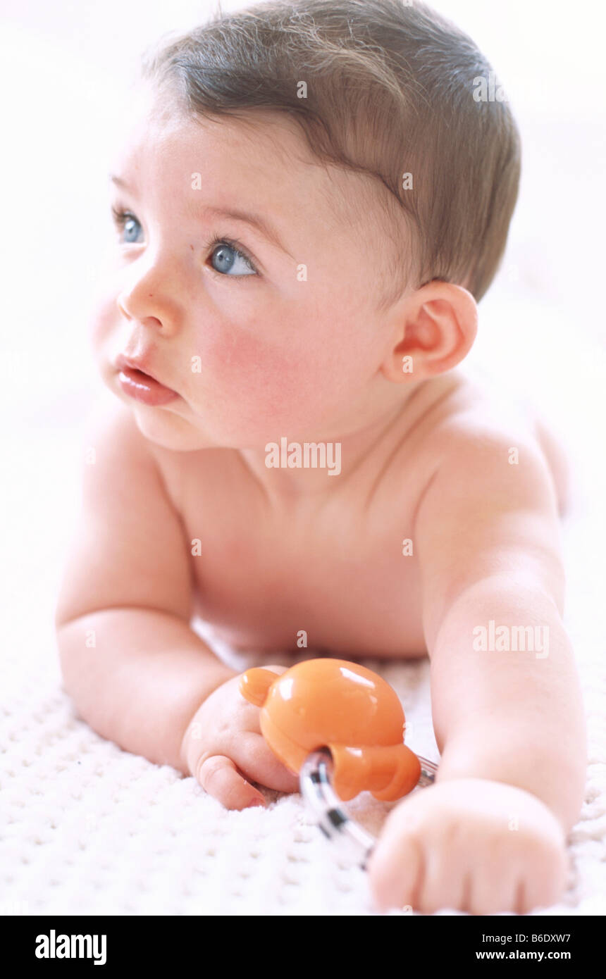 Baby boy. Distracted 6-month-old baby boy holding a toy Stock Photo - Alamy