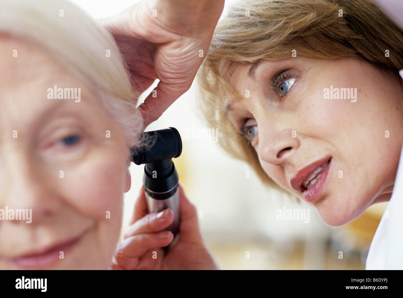 Ear examination. General practice doctor examining a 63-year-old woman ...