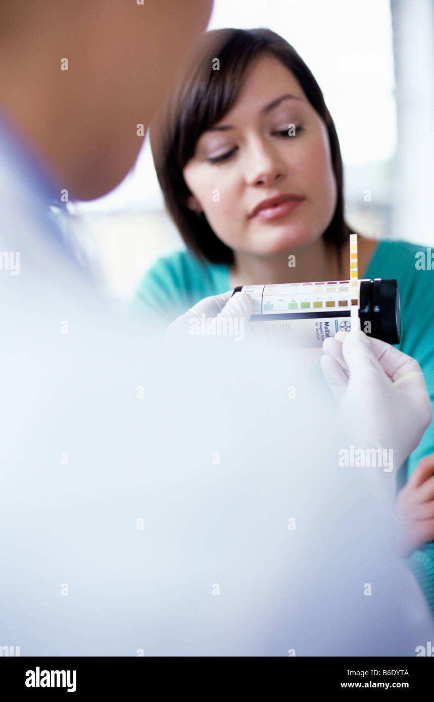 Urine analysis, General practice doctor comparing a multiple test stick ...