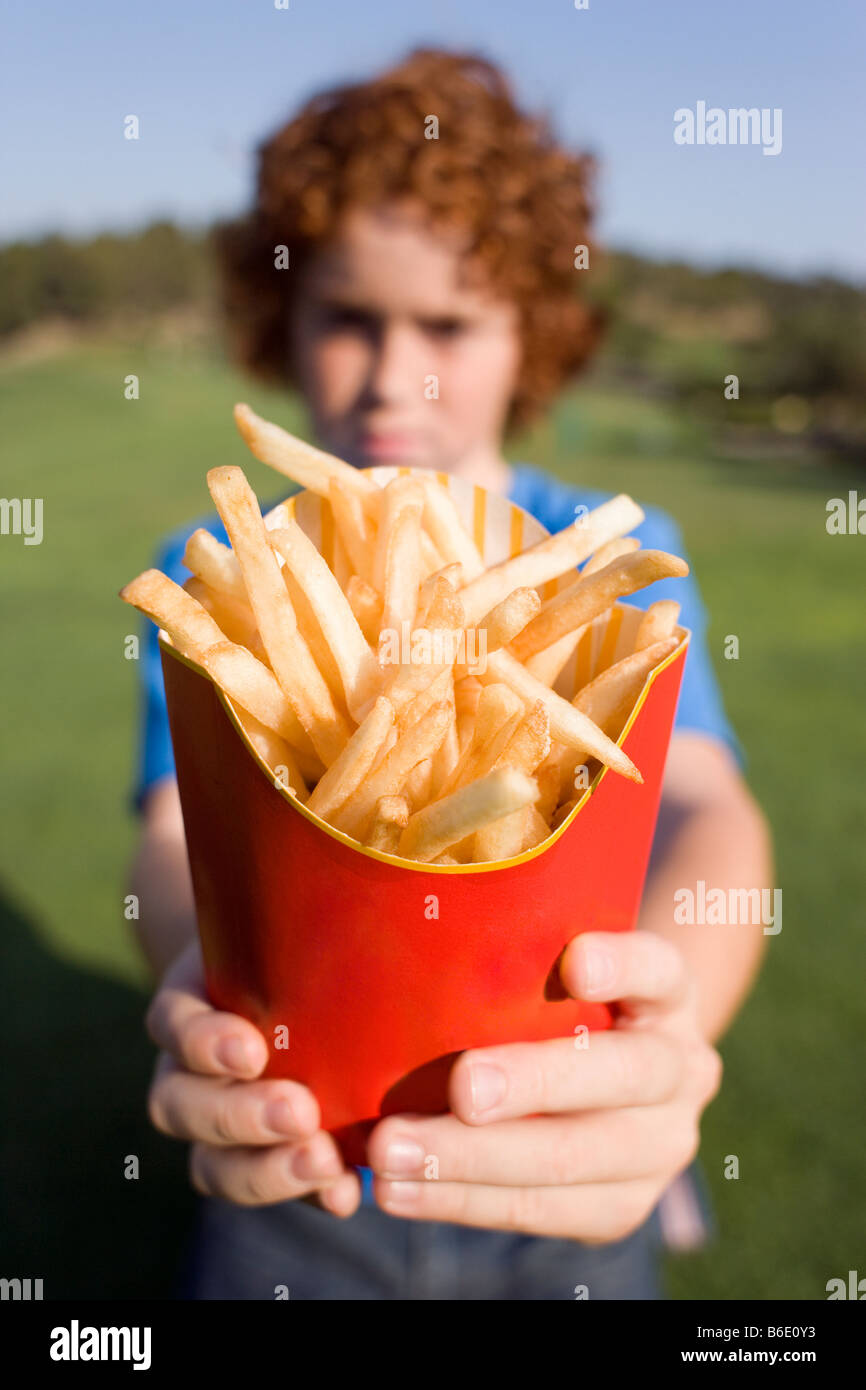 Boy holding chips. These are fried chipped potato portions. They are a ...
