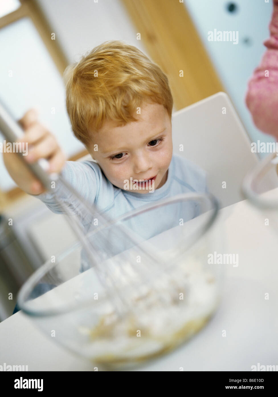 Making cakes. Three year old boy mixing together the ingredients for a ...
