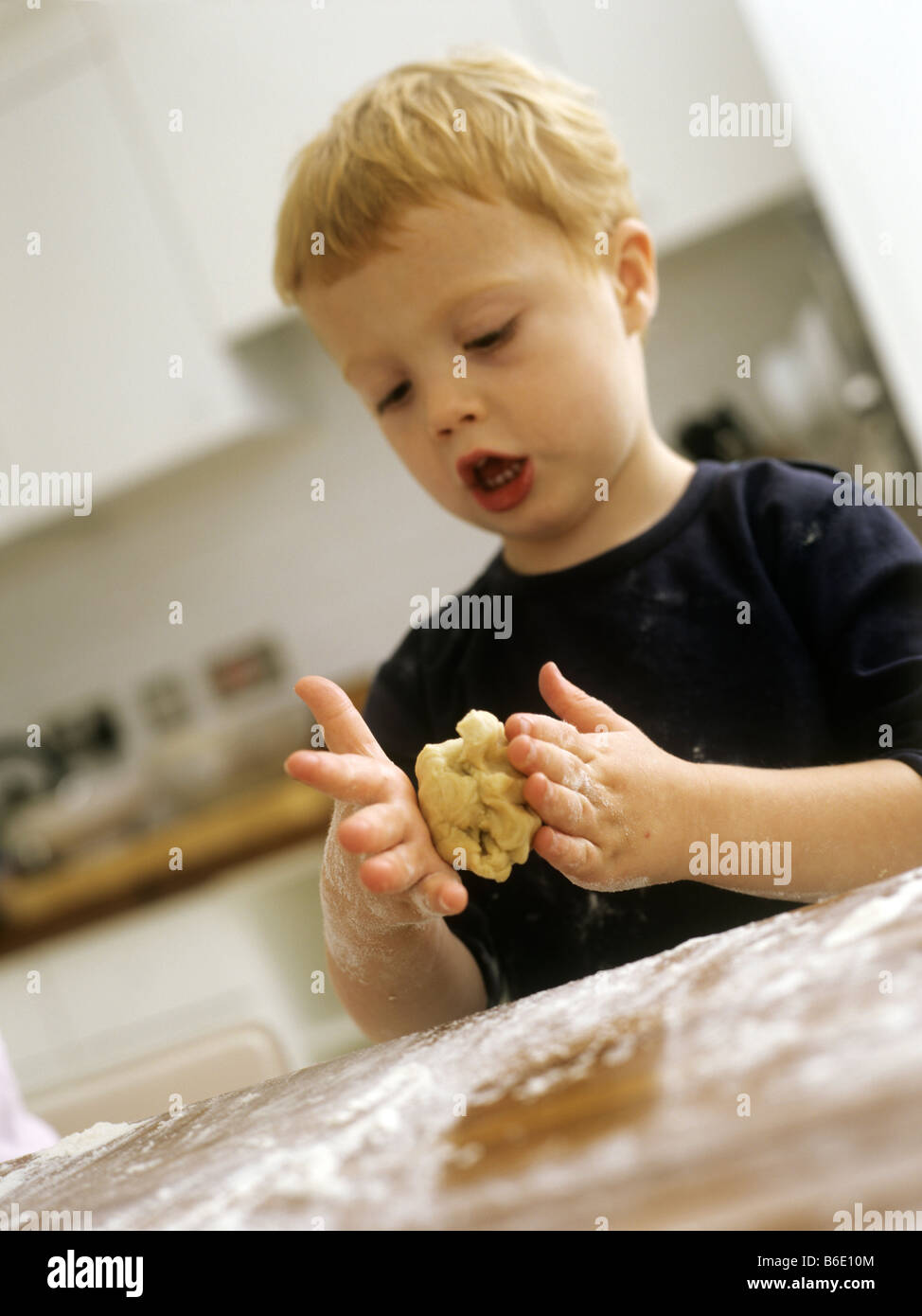 Making biscuits. Three year old boy singing whilst rolling a biscuit ...