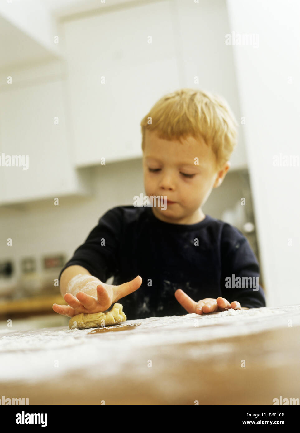 Making biscuits. Three year old boy singing whilst rolling a biscuit ...