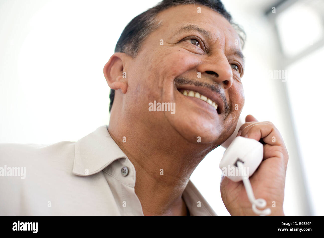 Man listening to someone talking on a telephone Stock Photo - Alamy