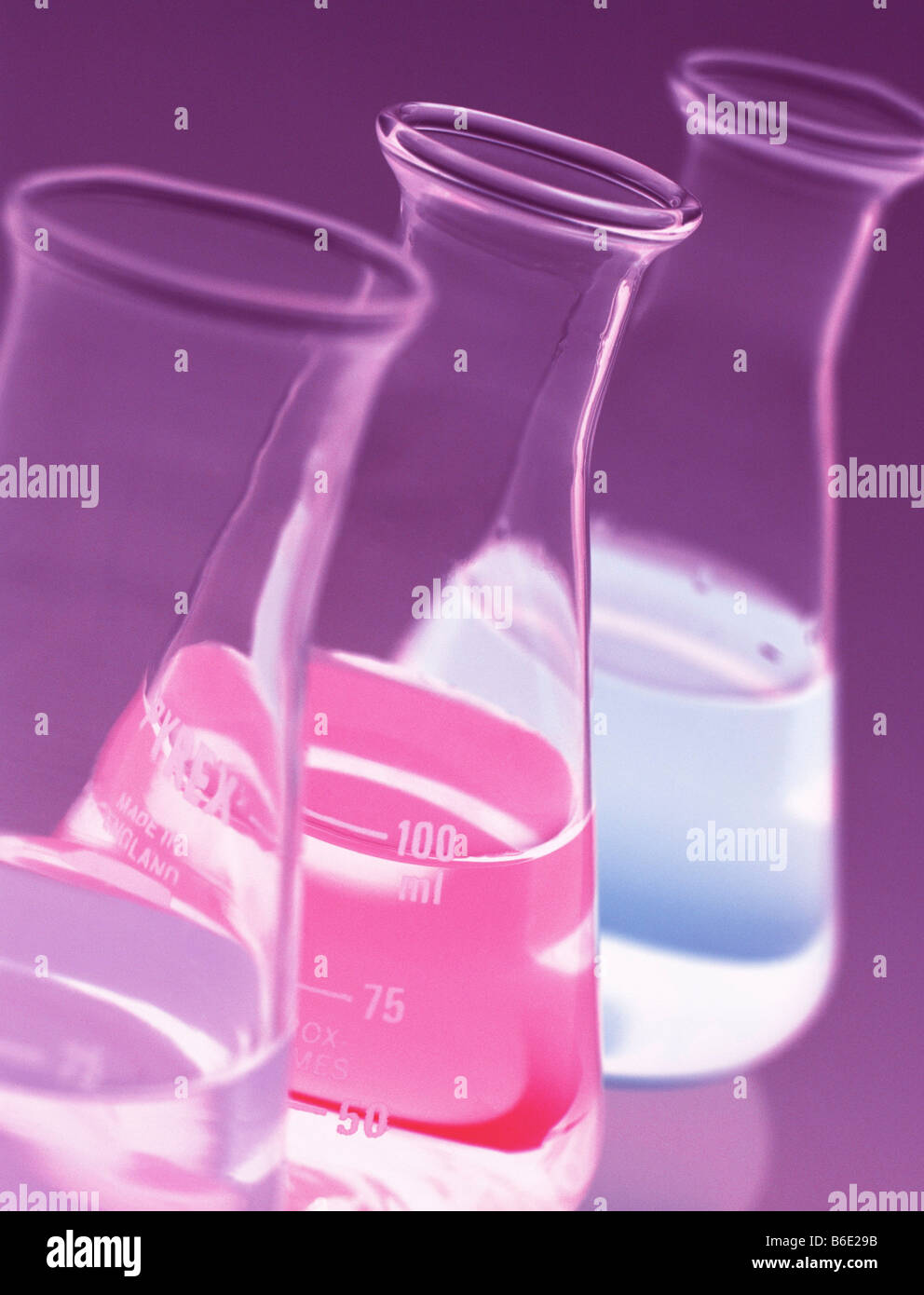 Conical flasks. Three conical flasks containing coloured solutions ...