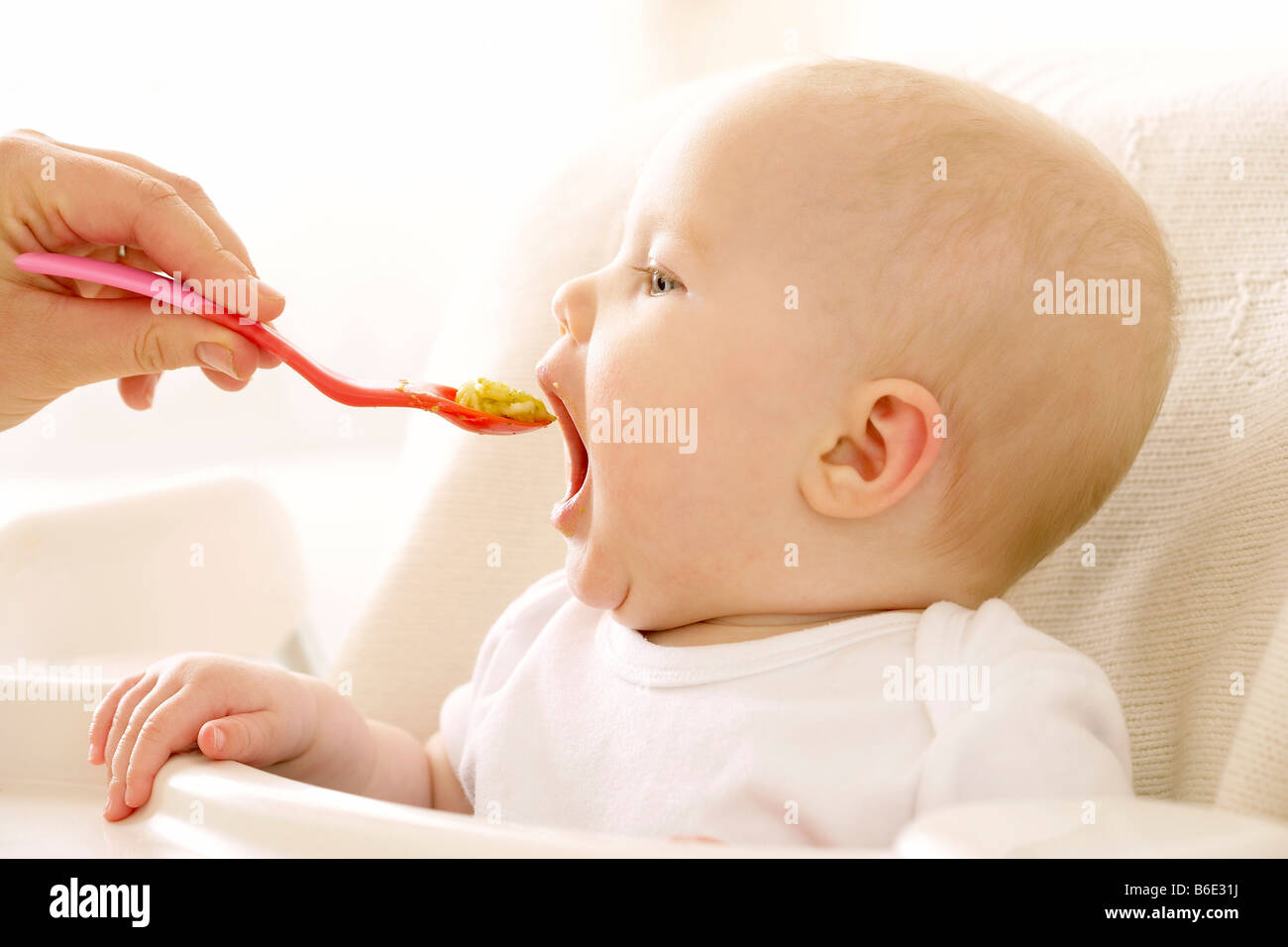 Baby girl (6-11 months) being spoon-fed Stock Photo - Alamy