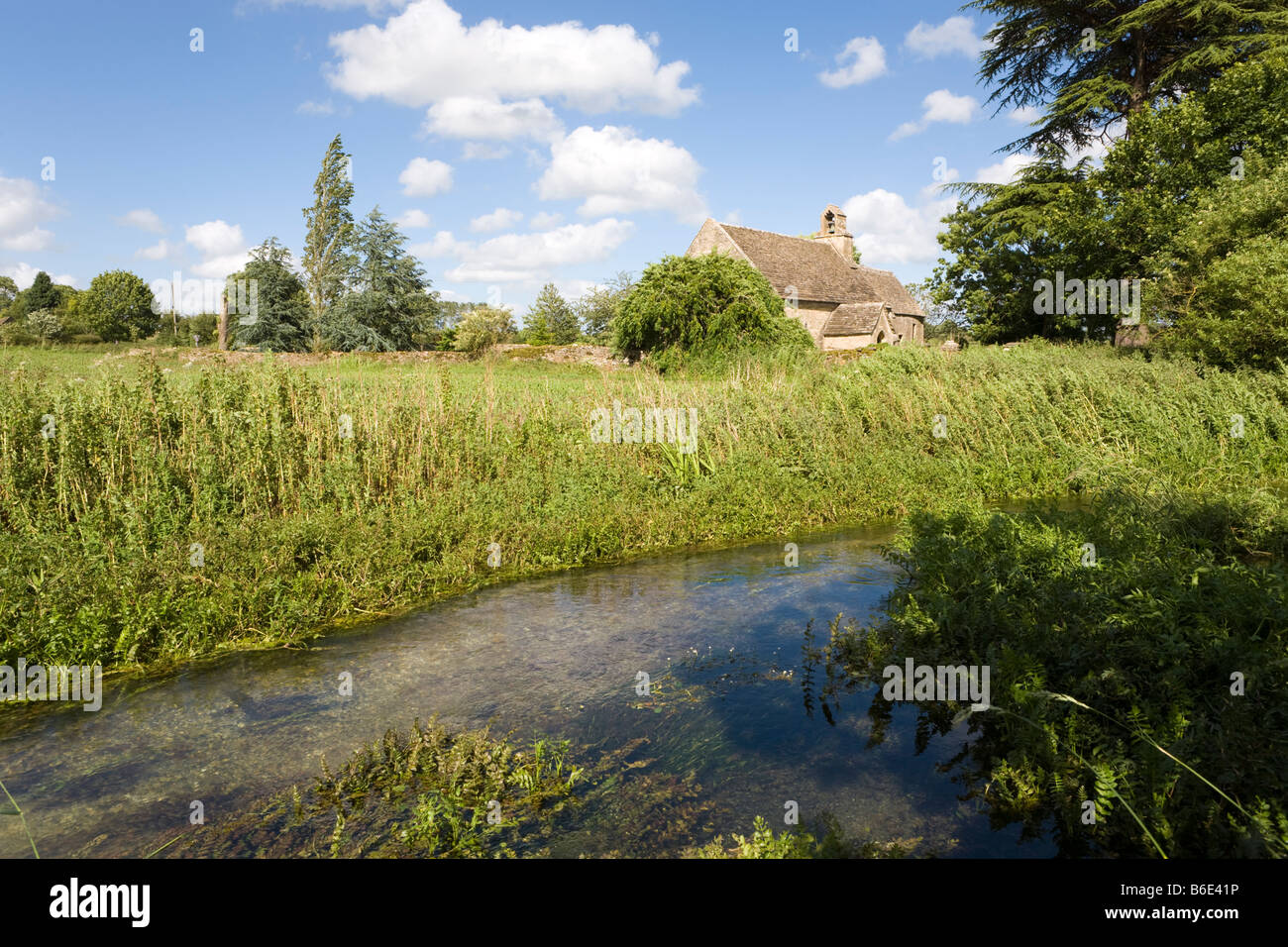 The 12th century Cotswold church of St Mary beside the Ampney Brook at ...