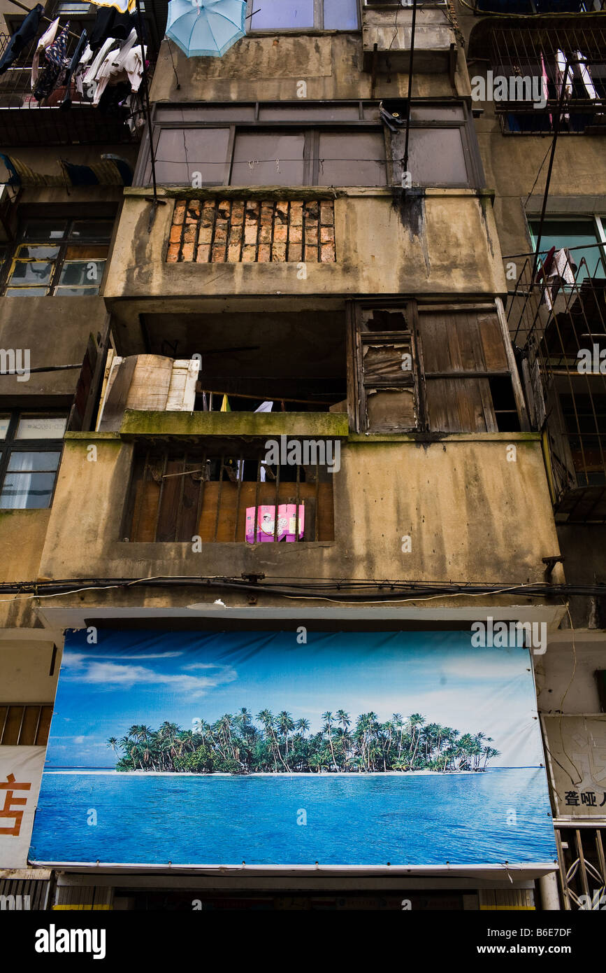 A poster showing a tropical island is hung below a rundown apartment ...