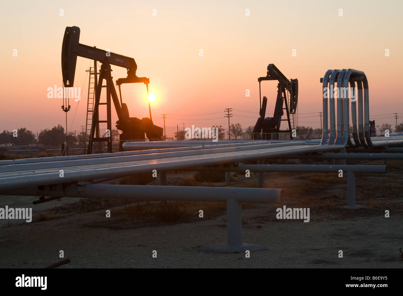 Sunrise illuminates an oil drilling derrick near Taft, California Stock ...