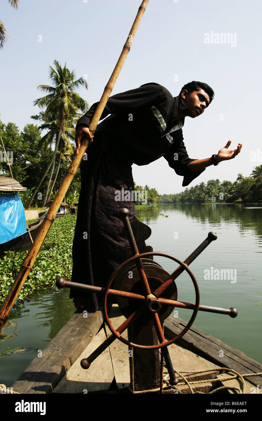 A boat captain steers a houseboat along the backwaters of Kerala India ...