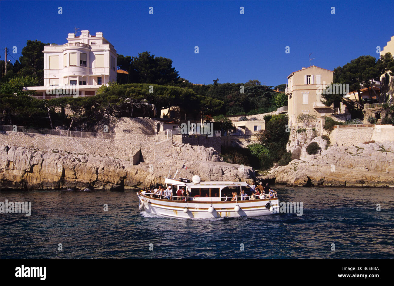 A pleasure boat with tourists cruises past luxury houses in the Bay of ...