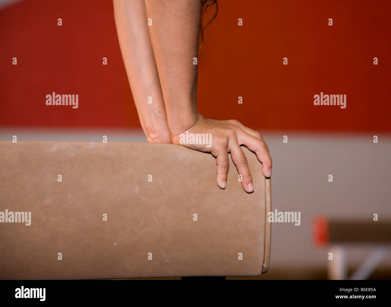 The hand of a young female gymnast grips the balance beam during a ...