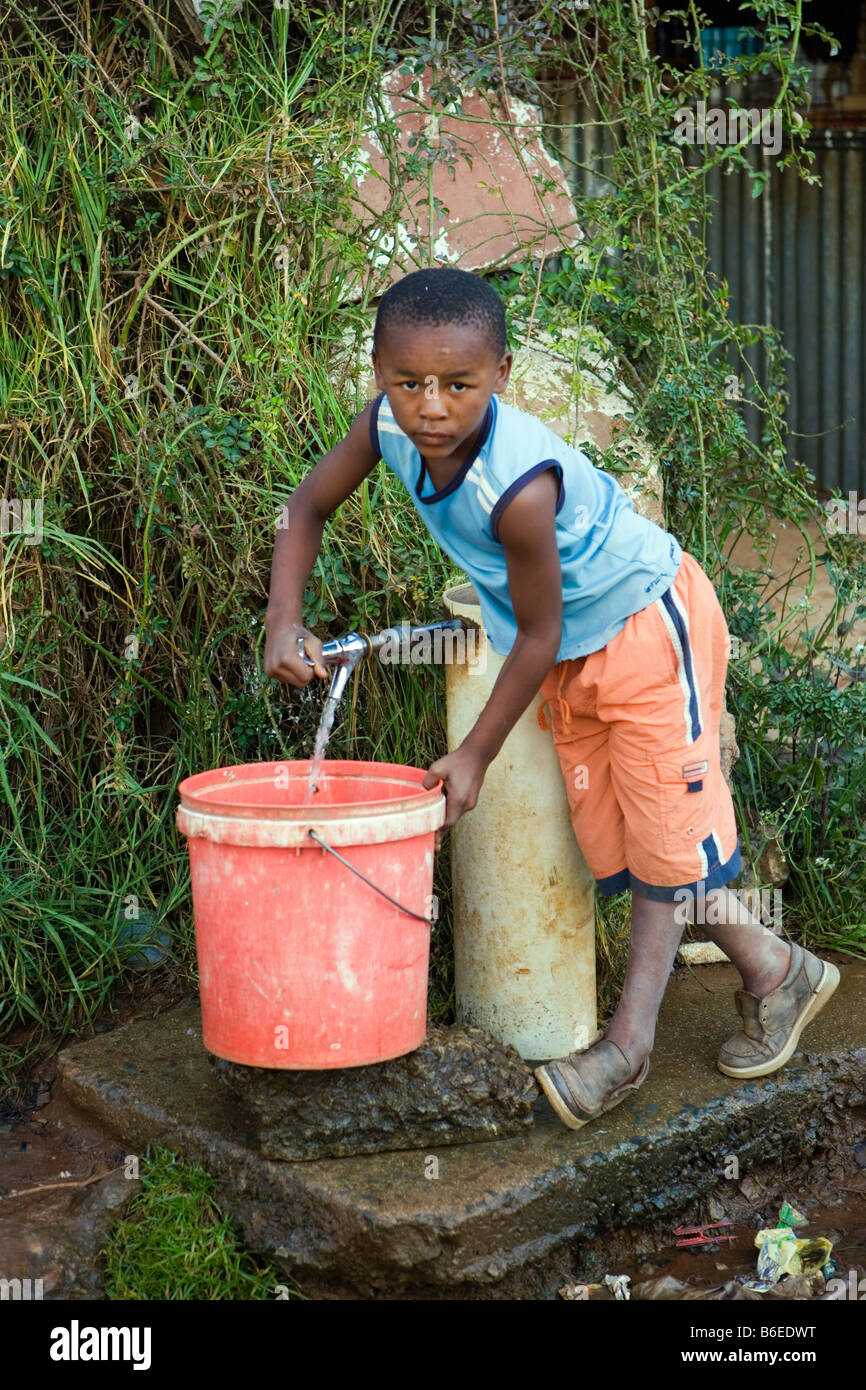 South Africa, Johannesburg, Soweto, Slums or squatter camp. Boy at tap ...