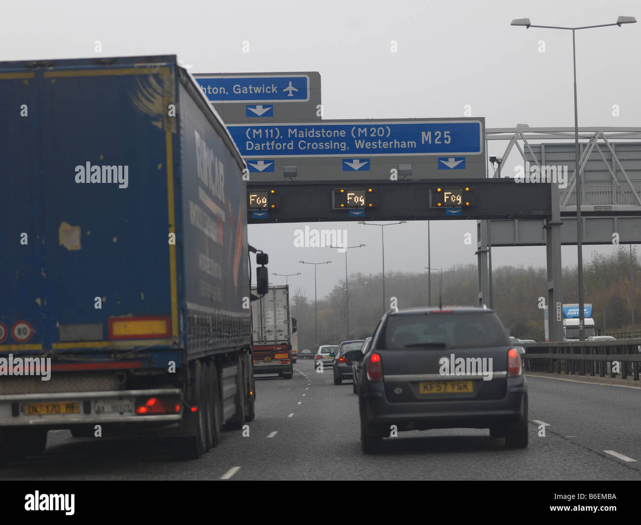 Traffic on M25 Motorway in Surrey with fog warning signs Stock Photo ...