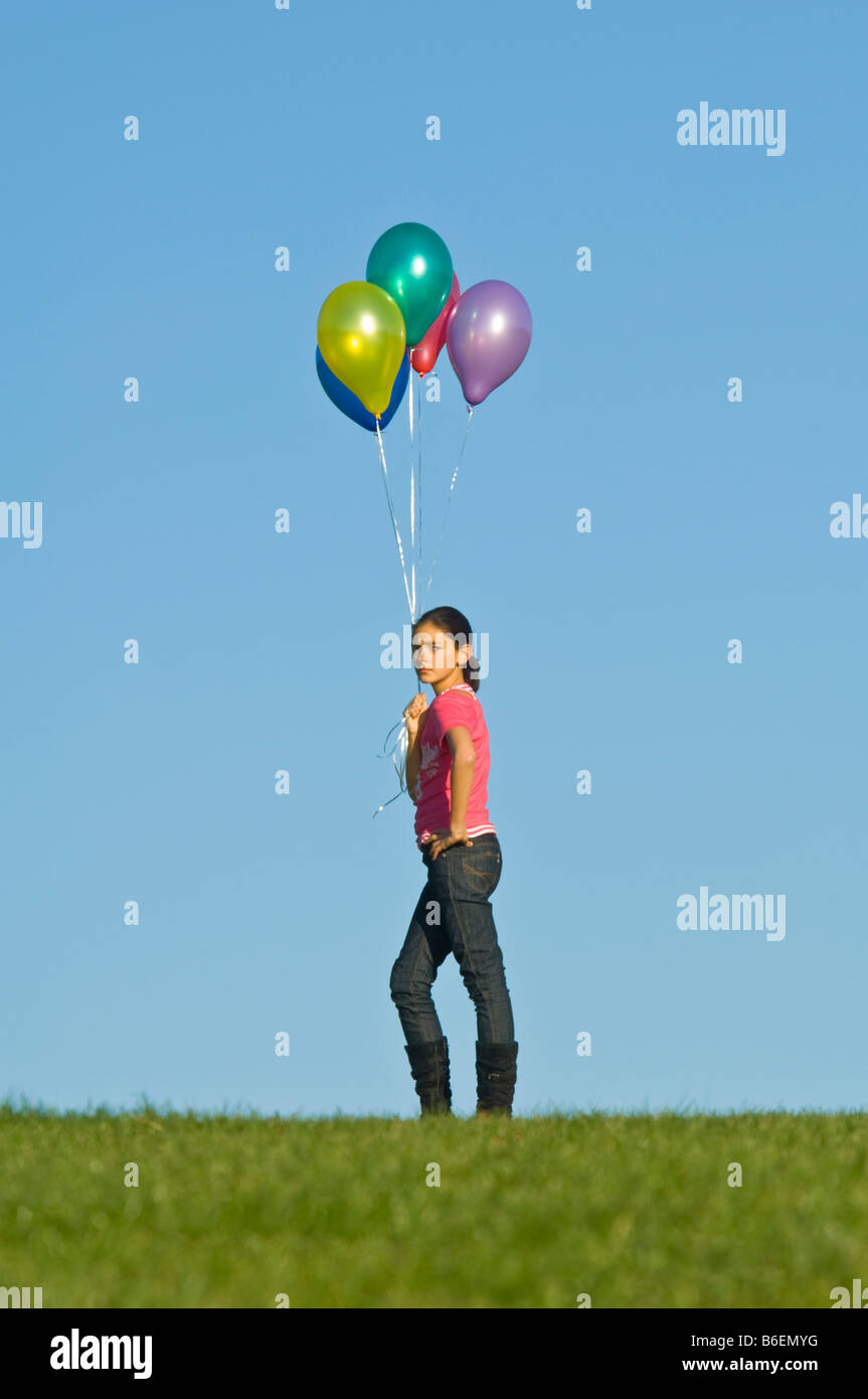 A young unhappy girl (11) with a bunch of colourful helium filled ...