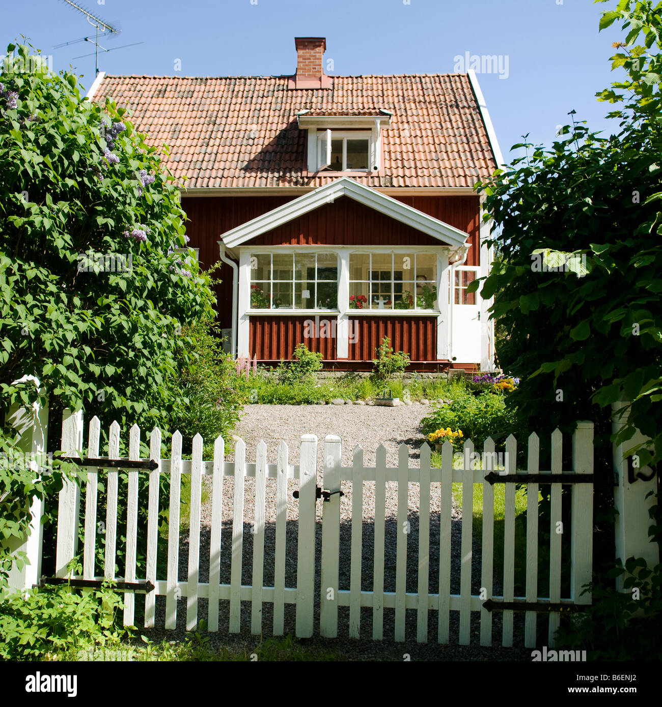 White gate in front of red house Stock Photo - Alamy