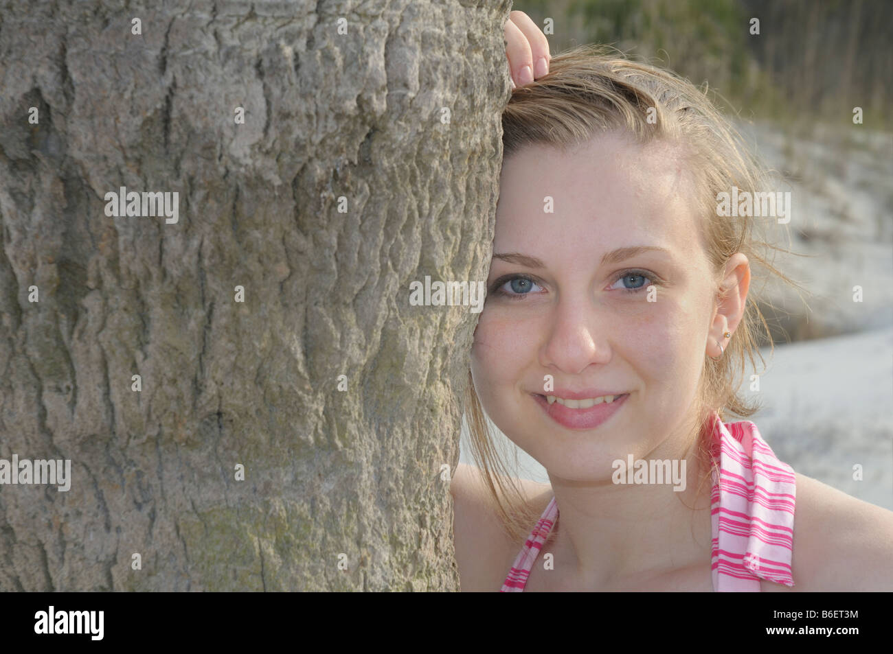 Pretty Teen Girl With Blue Eyes Stands By A Palm Tree And Smiles Photo