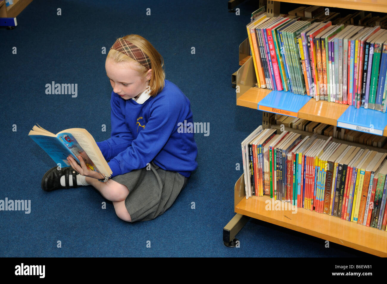 Childrens school library schoolgirl reading a book selected from the ...