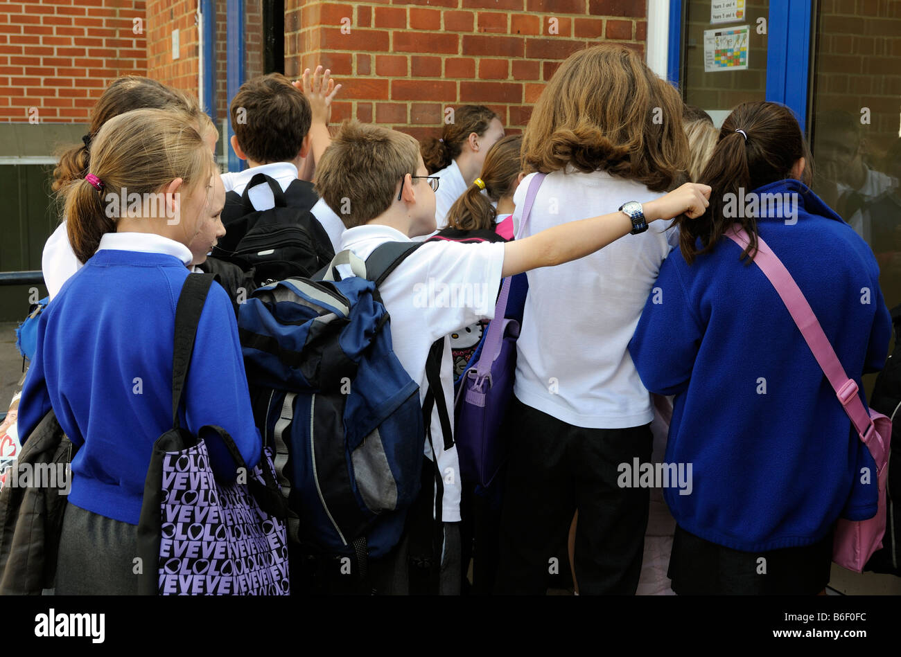 Boy bully pulling girls hair who is standing in line to enter primary ...