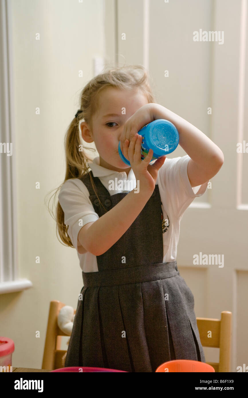 five year old girl has a drink from a blue plastic beaker Stock Photo ...