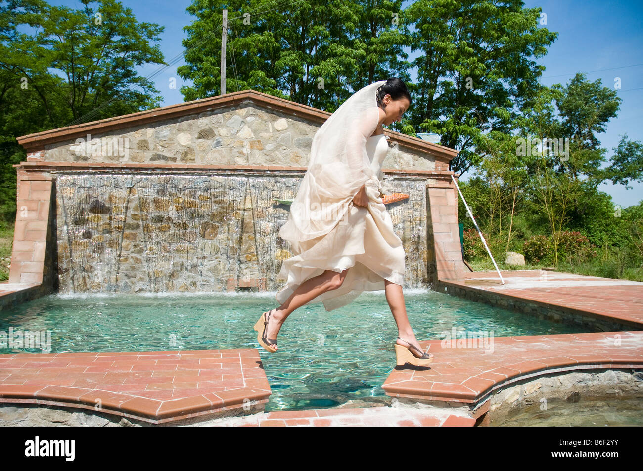 Bride jumping across a pool Stock Photo - Alamy