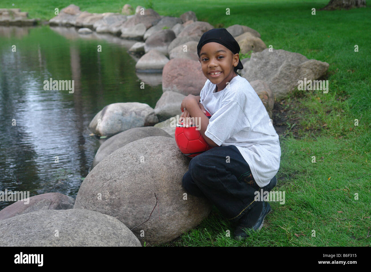 Boy kneeling by pond Stock Photo - Alamy