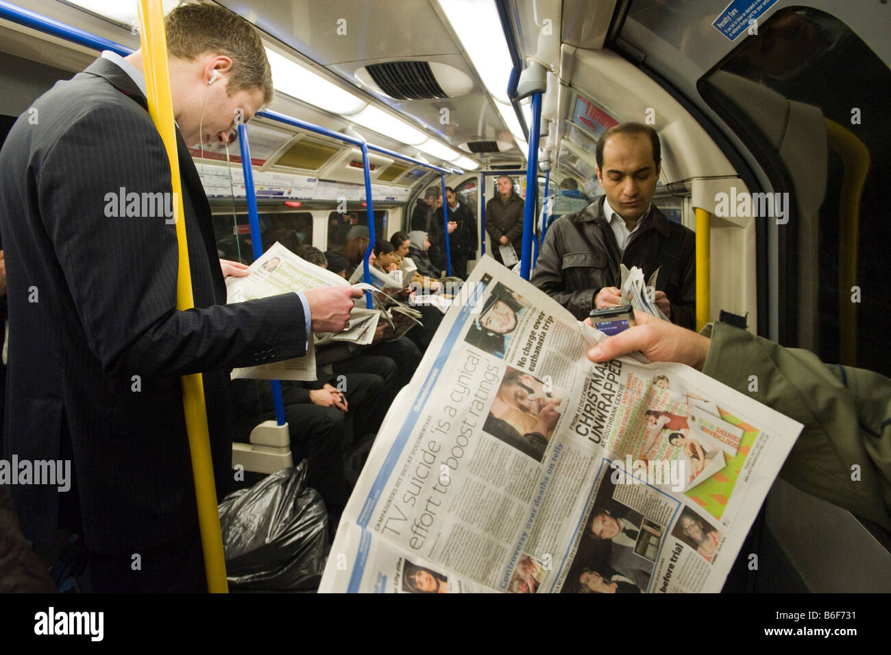 Commuters on underground train reading newspapers London United Kingdom ...