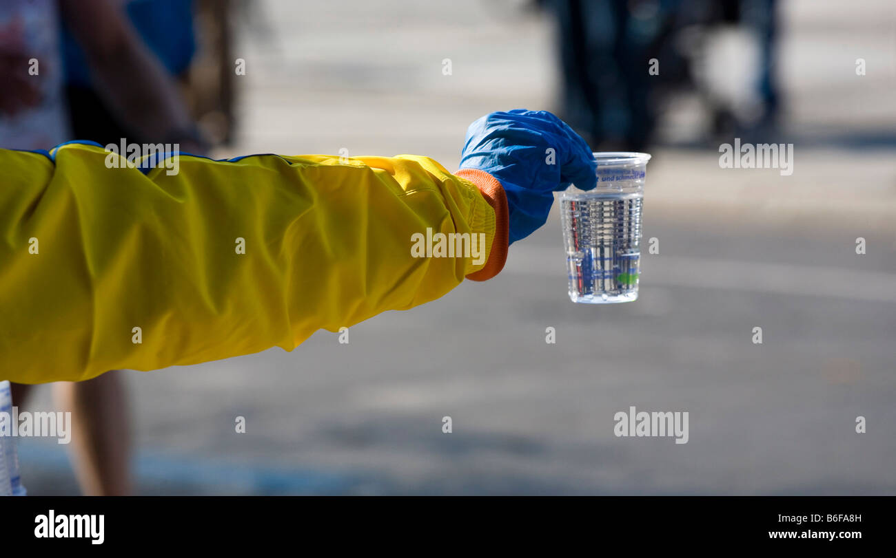 Arm of a helper holding out a cup of water for the runners of the ...