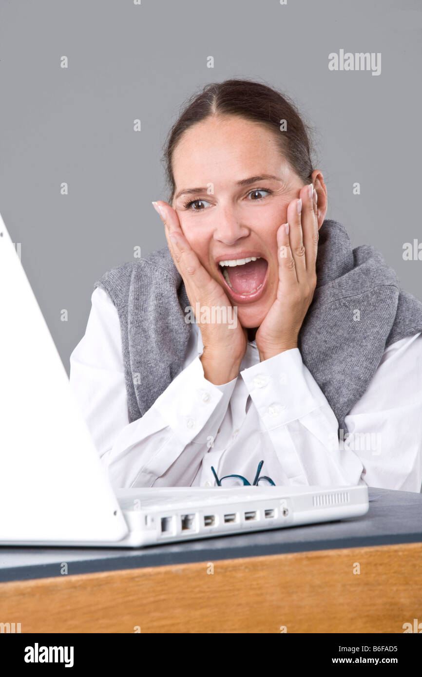 Young woman working on her laptop, very pleased Stock Photo - Alamy