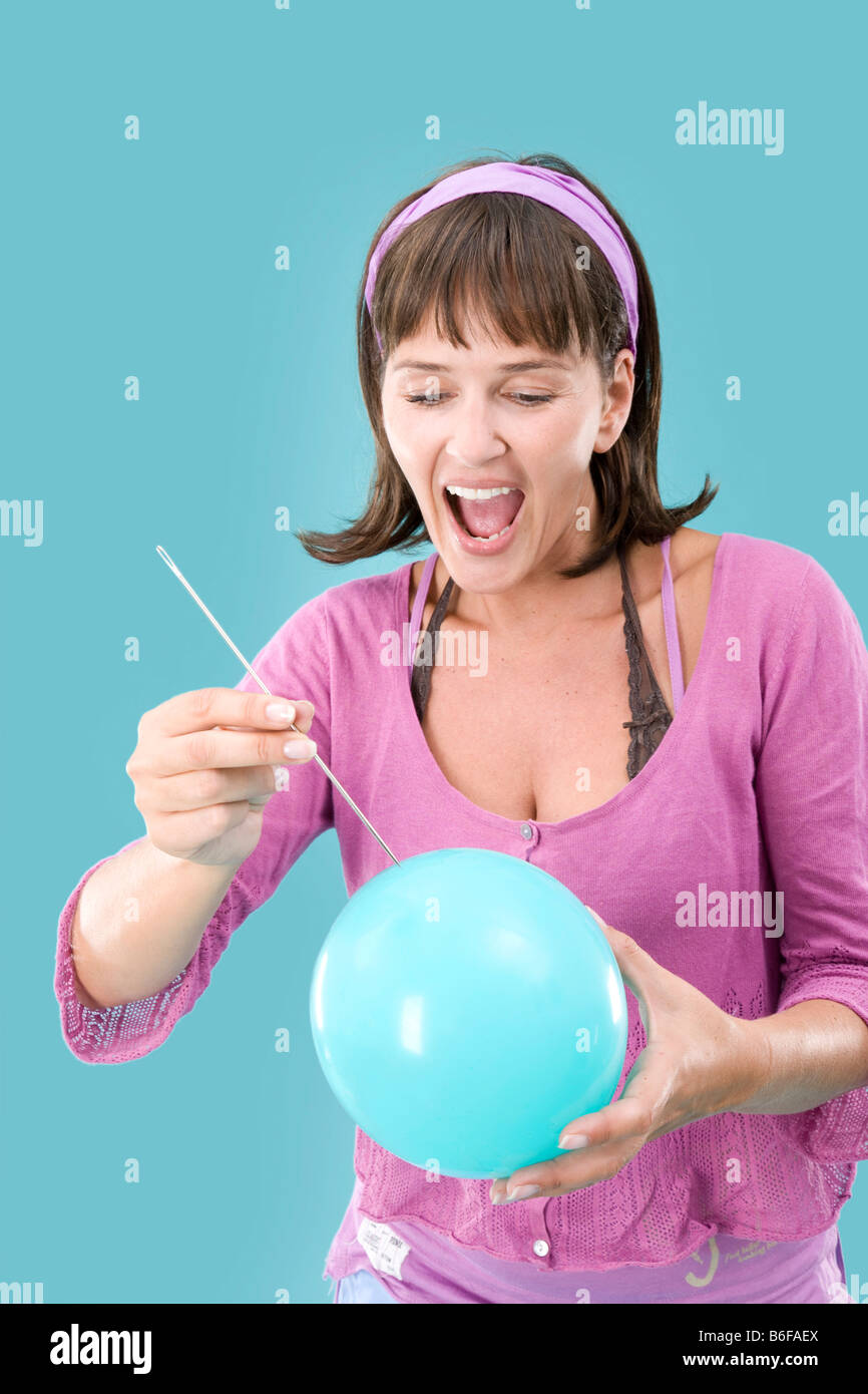 Girl sticking a needle in a balloon Stock Photo - Alamy