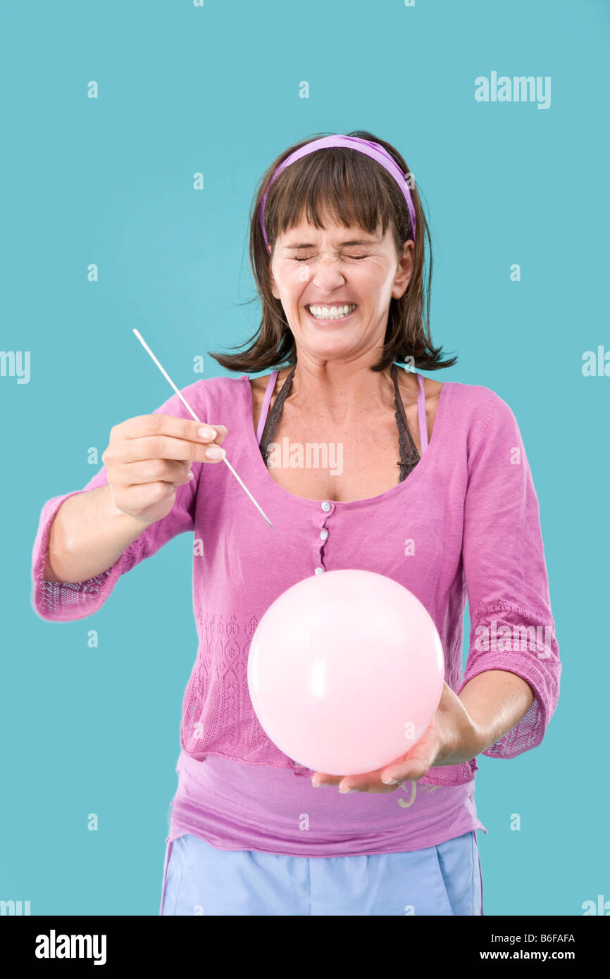 Girl sticking a needle in a balloon Stock Photo - Alamy