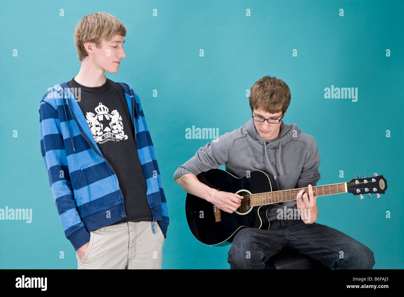 Two young men, one of them playing guitar Stock Photo - Alamy
