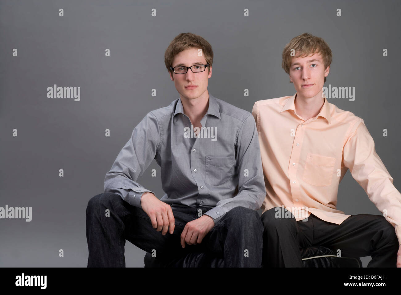 Two boys sitting next to each other hi-res stock photography and images ...