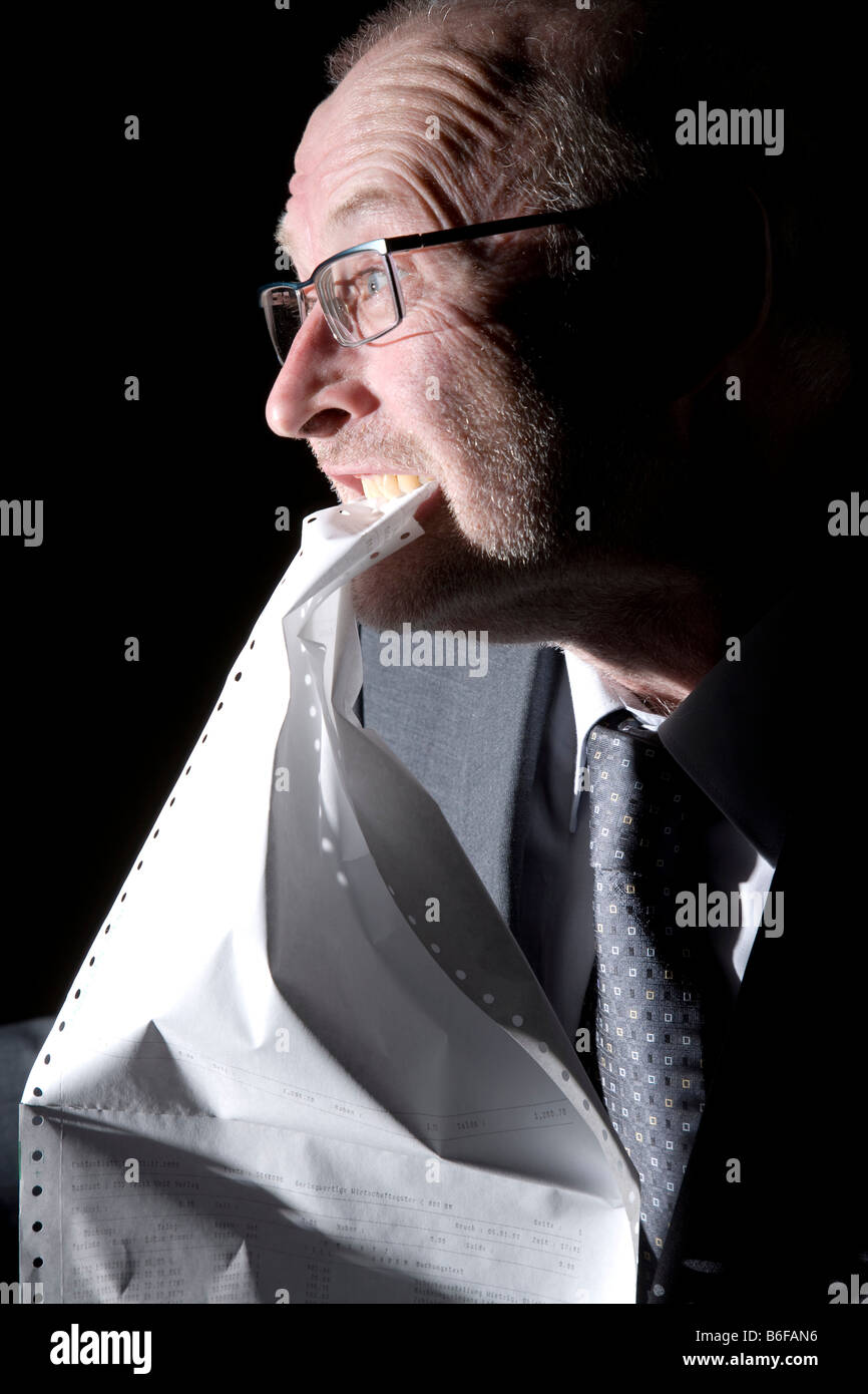 Businessman studying a strip of perforated computer paper, stock quotes ...