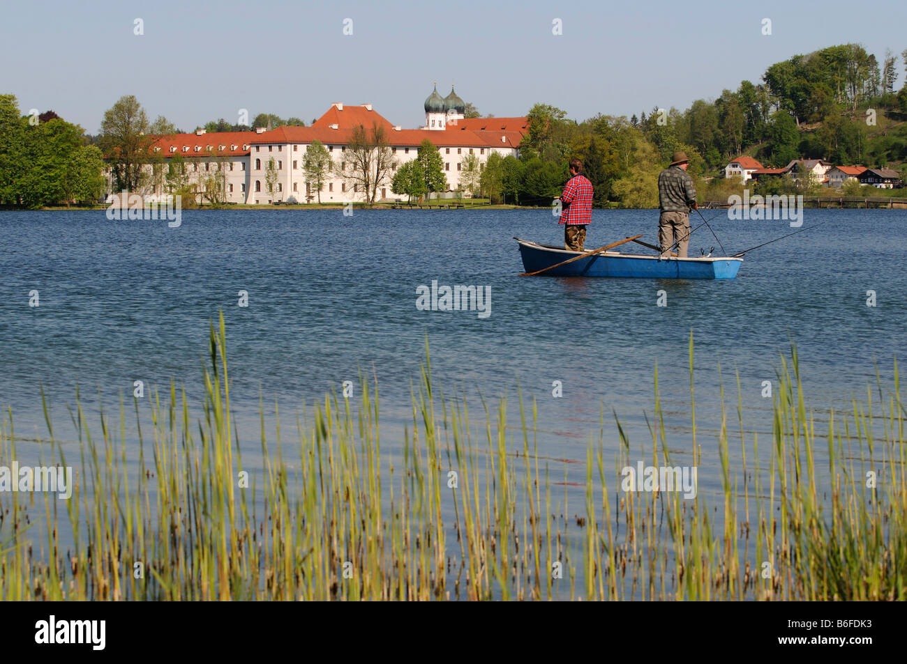 Fisherman on Lake Seeon, at back Seeon Convent, Seeon, Chiemgau ...