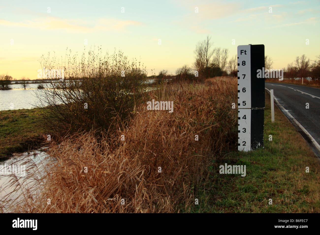A water depth marker at the side of a main road and a flooded field ...