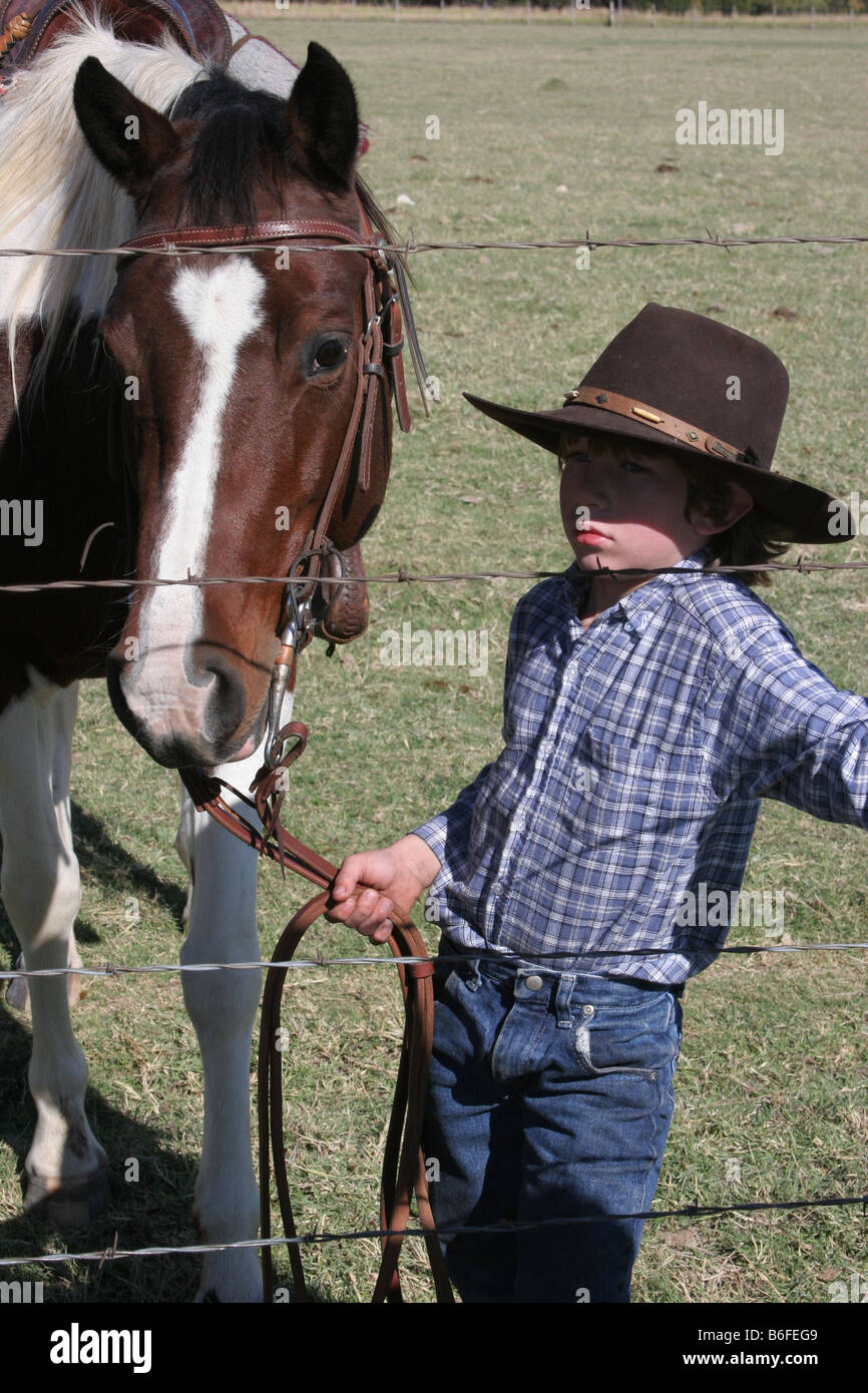 A young cowboy and his horse taking a break in the pasture on the ranch ...