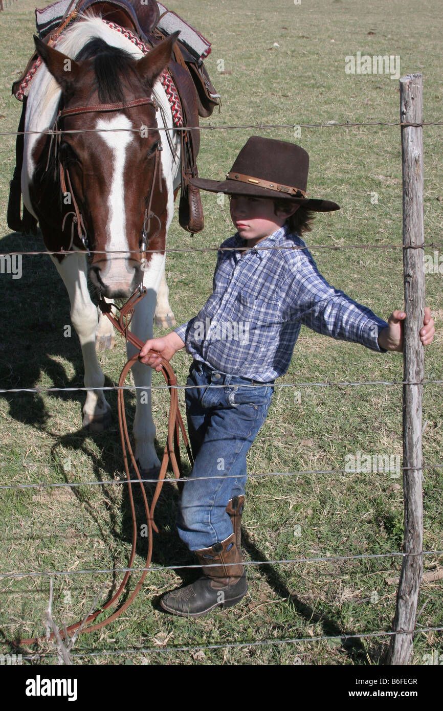 A young cowboy and his horse taking a break in the pasture on the ranch ...