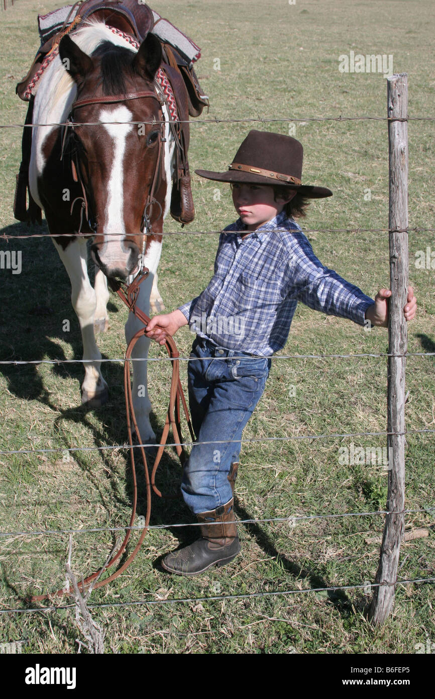 A young cowboy and his horse taking a break in the pasture on the ranch ...